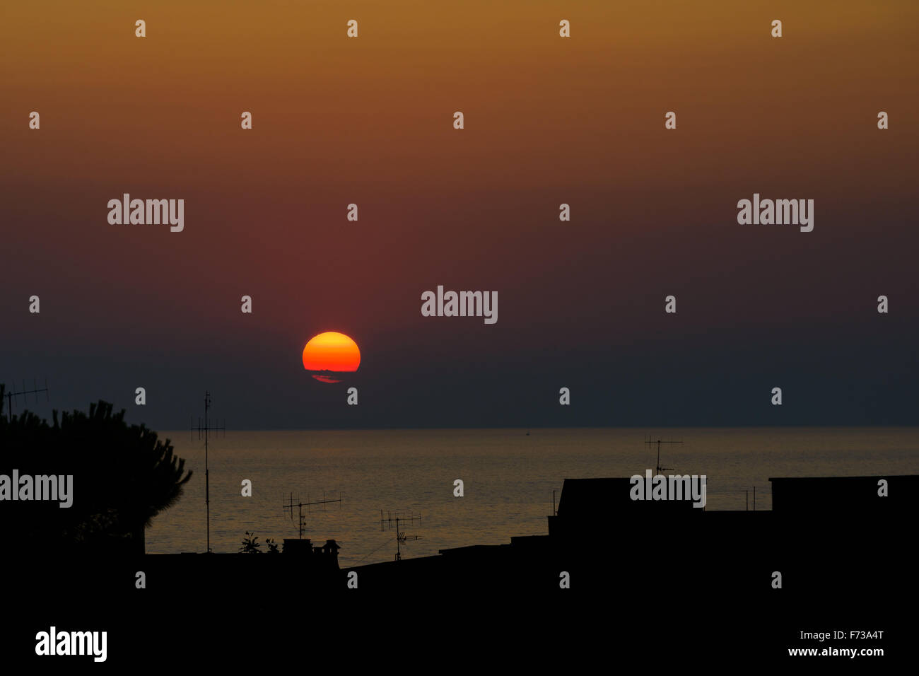 Big round red and orange sun go down in the sea Stock Photo - Alamy