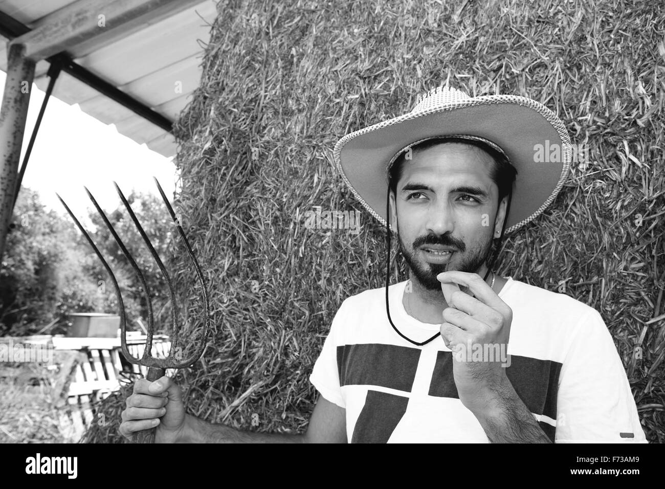 handsome cowboy holding a pitch fork in stable Stock Photo - Alamy