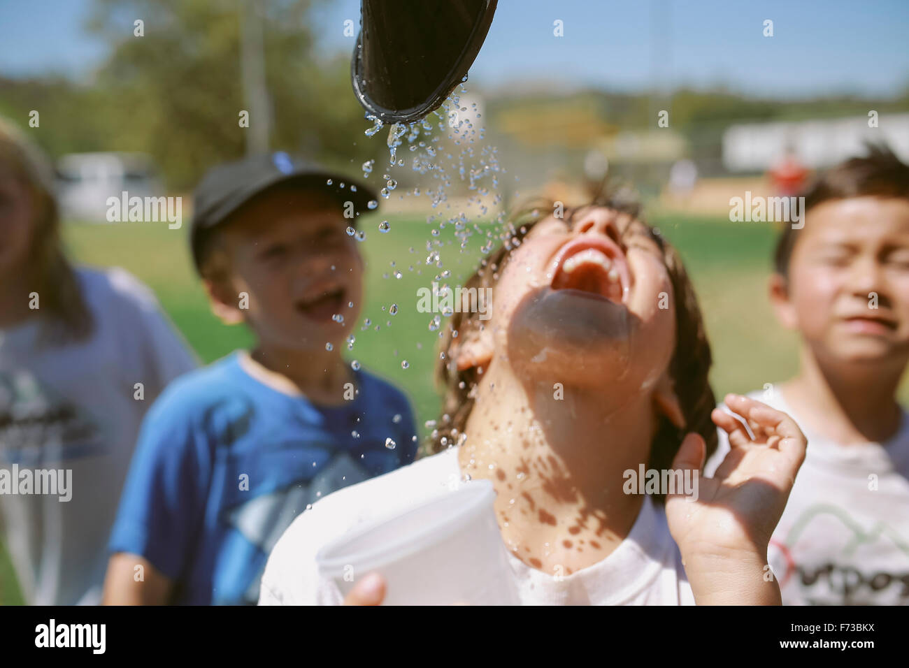 A group of young boys cool off with sprinkle of water in the break of a ...
