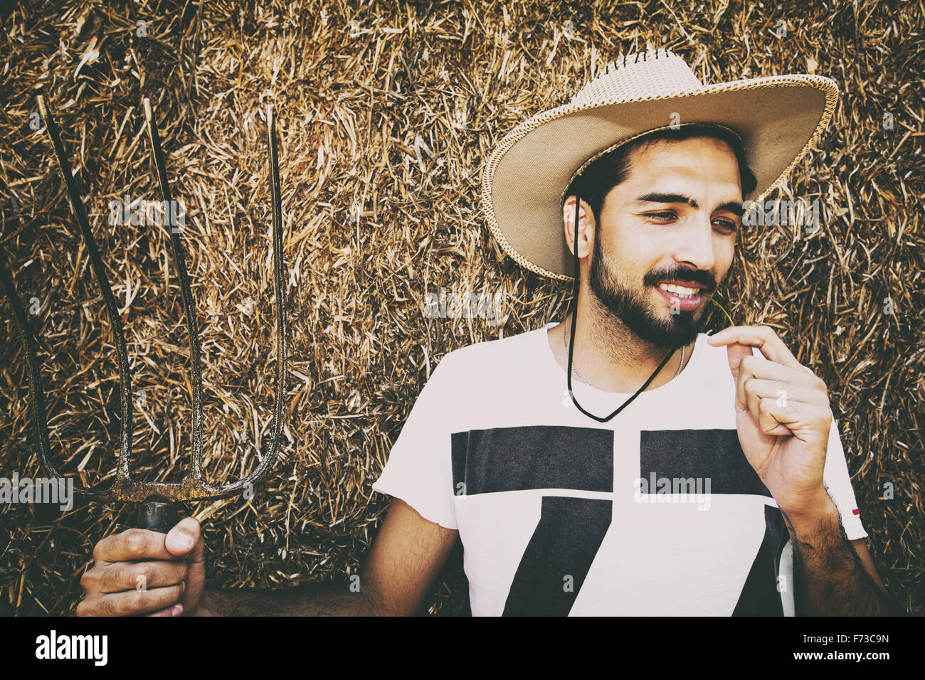handsome cowboy holding a pitch fork in stable Stock Photo - Alamy