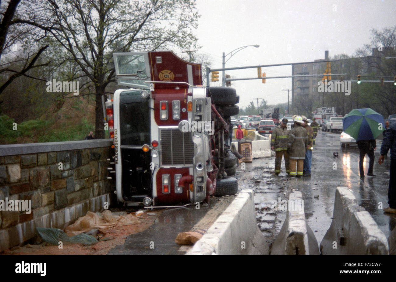 Firefighters examine a fire truck that flipped over on its side while ...