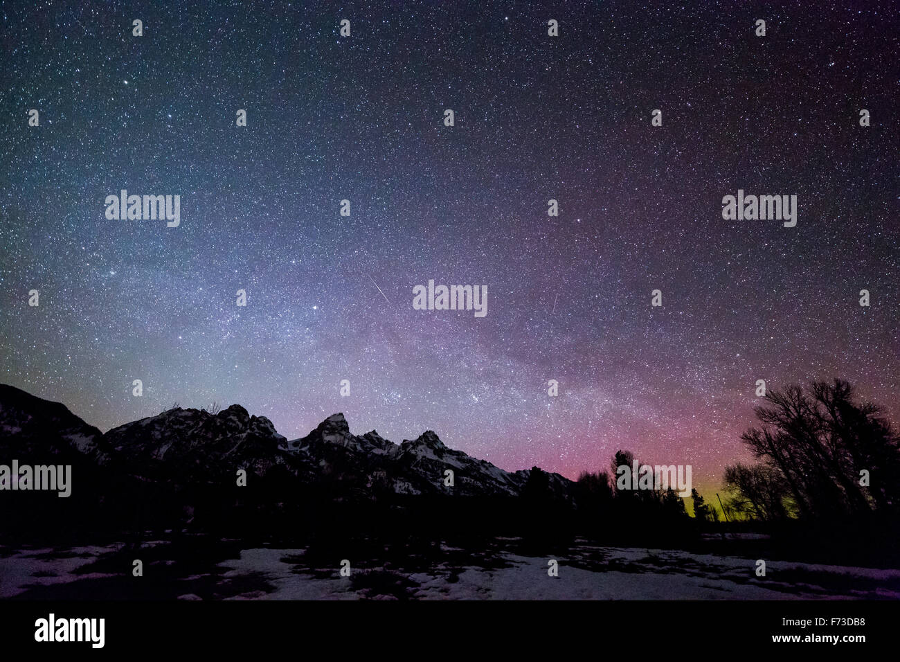 A meteor streaking above the Teton Mountains as northern lights glow in ...