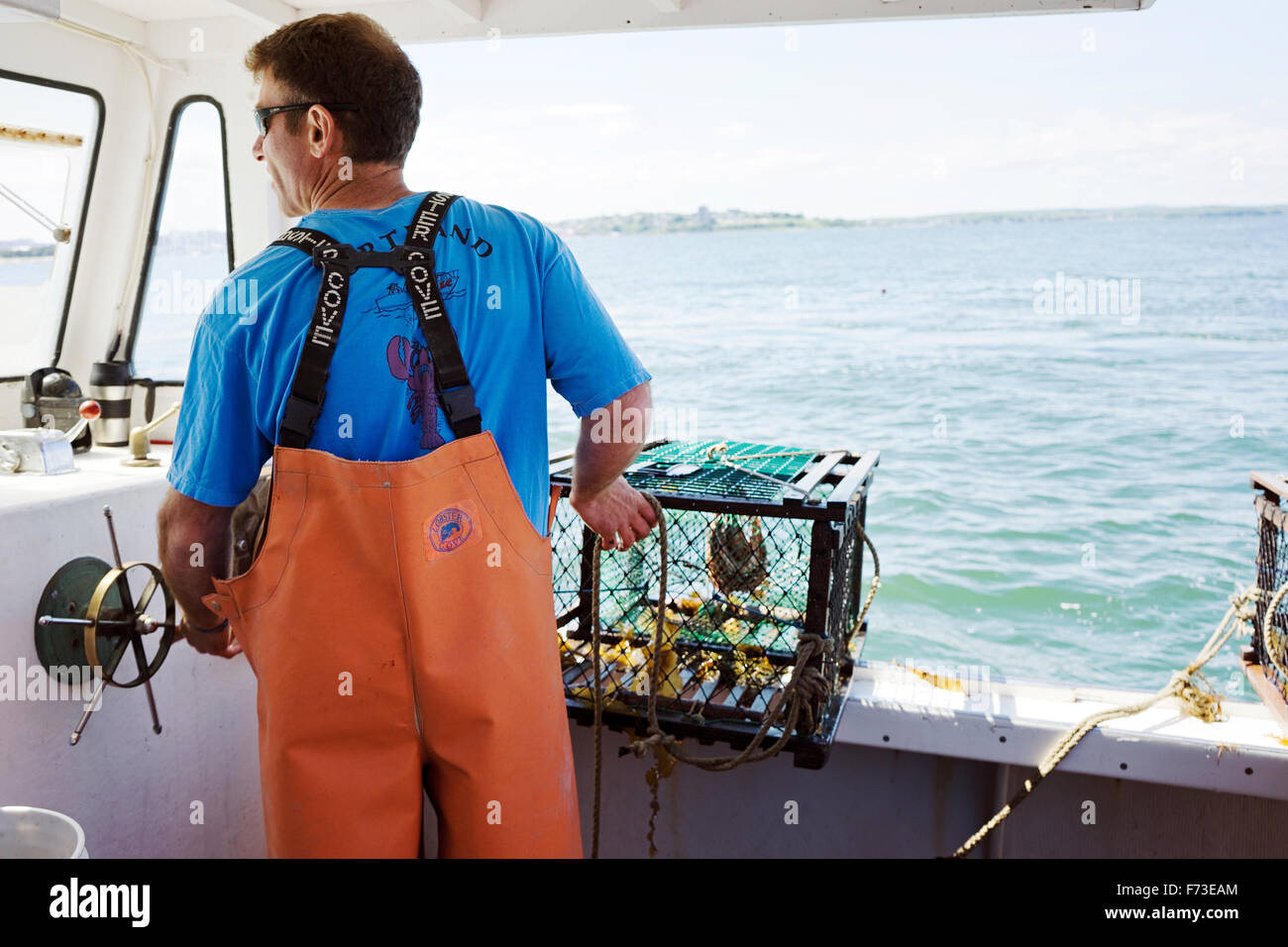 Lobster boat captain steering and about to place a lobster trap Stock ...