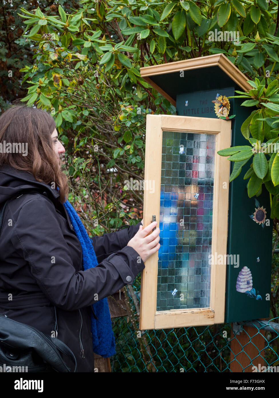 A pretty brunette girl uses A Little Free Library book exchange box on ...