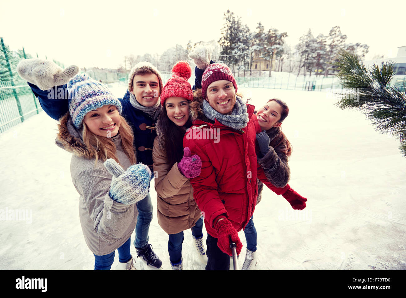 happy friends with smartphone on ice skating rink Stock Photo - Alamy