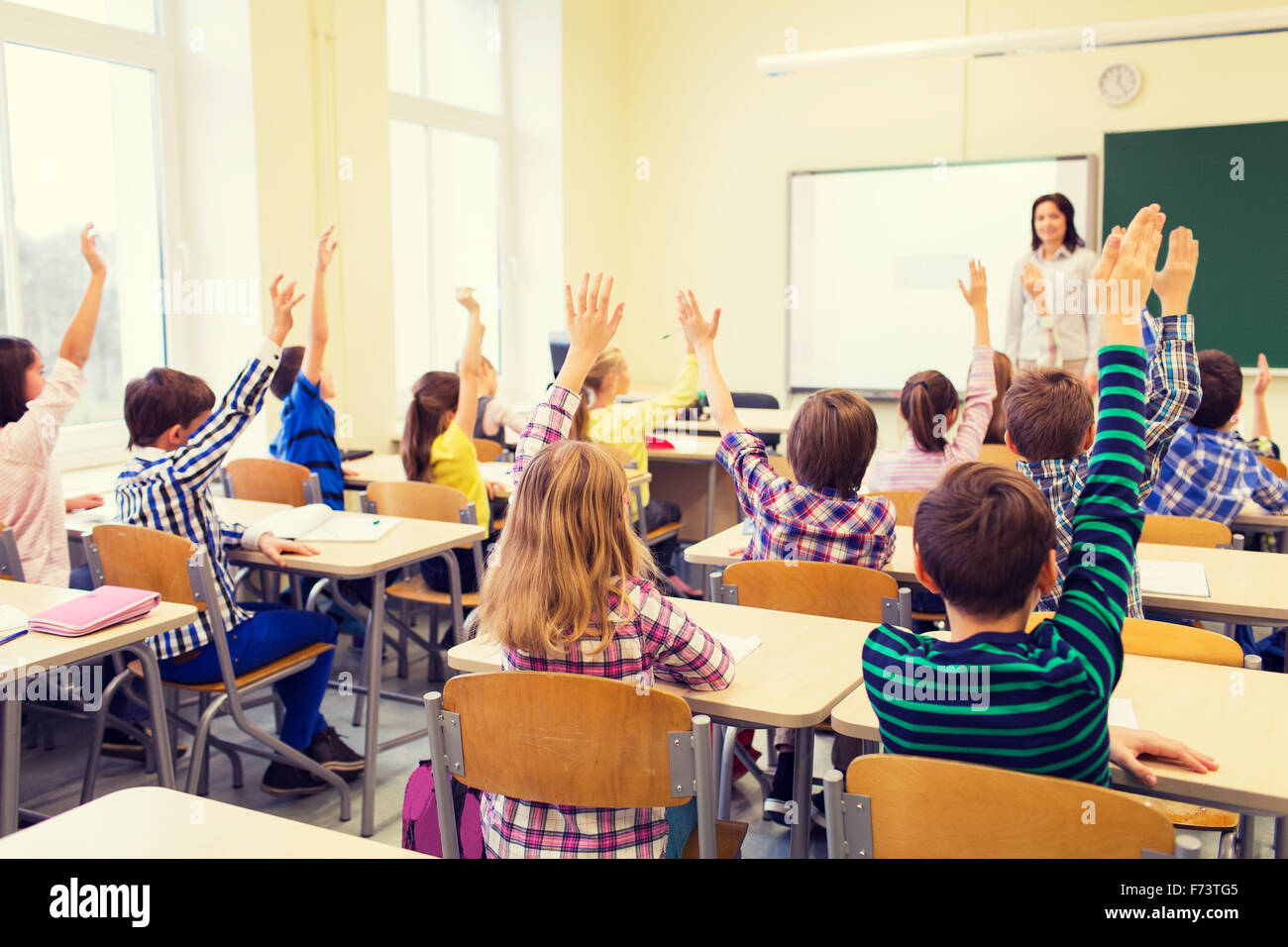 group of school kids raising hands in classroom Stock Photo - Alamy