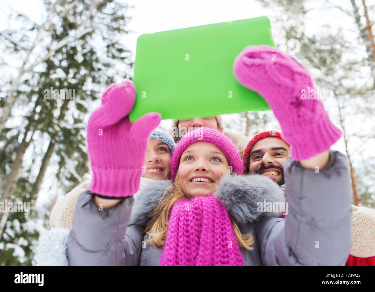 smiling friends with tablet pc in winter forest Stock Photo - Alamy