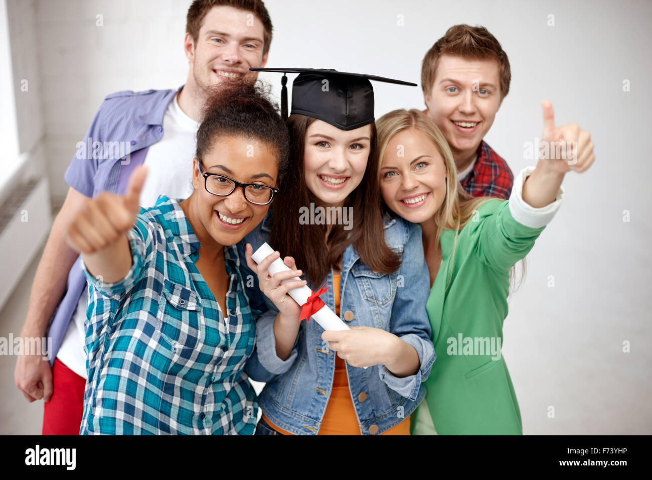 smiling students with diploma showing thumbs up Stock Photo - Alamy