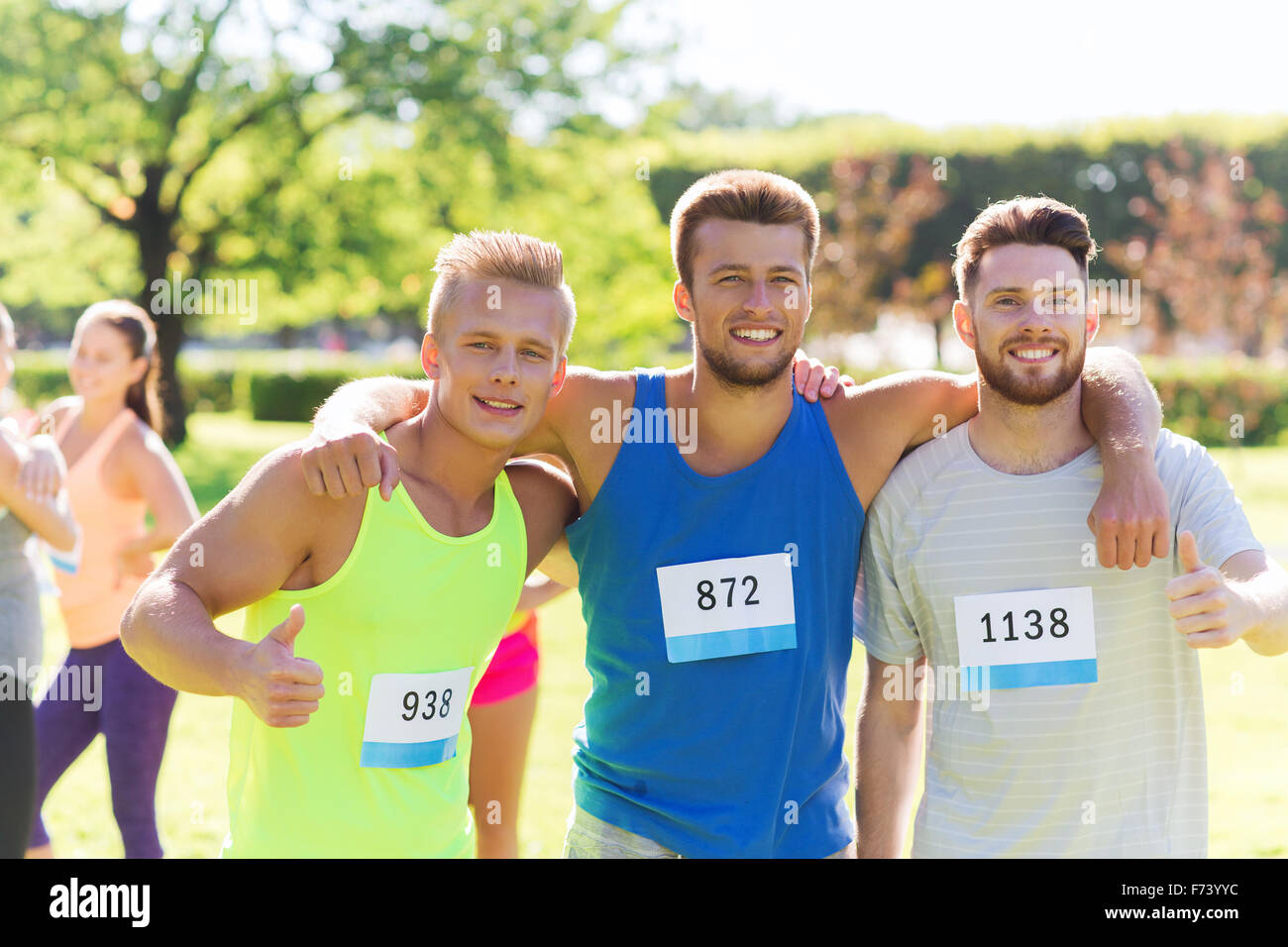 happy friends with racing badge numbers Stock Photo - Alamy