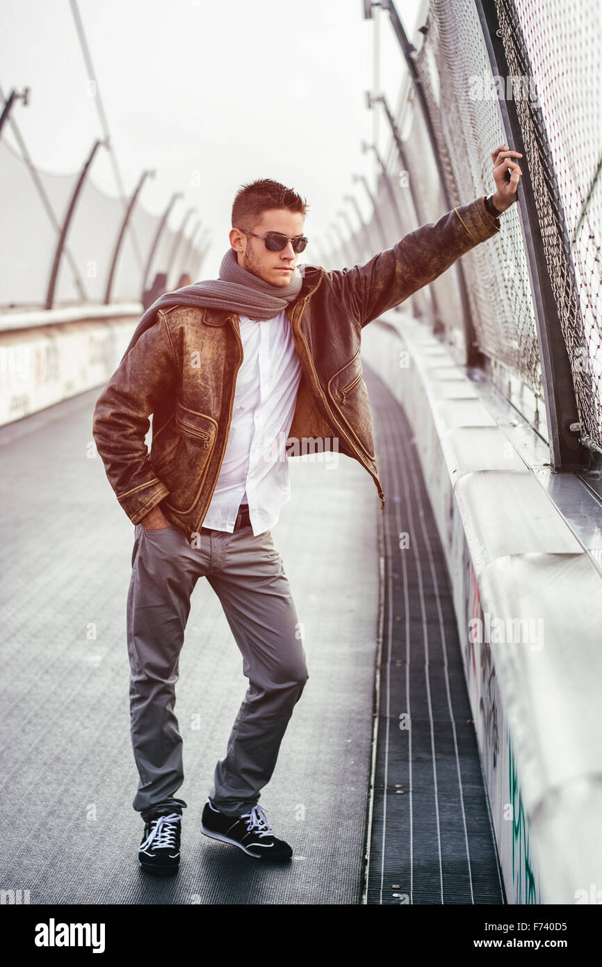 Handsome trendy young man standing on a sidewalk wearing a fashionable ...