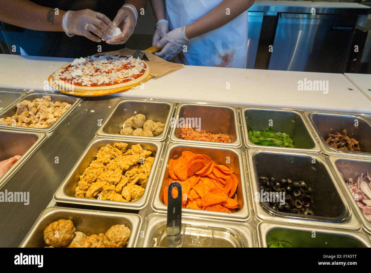 Employees construct a pizza right before the customers' eyes in ...