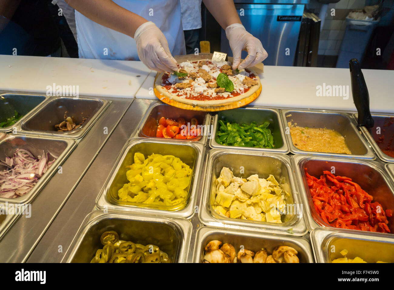 Employees construct a pizza right before the customers' eyes in ...