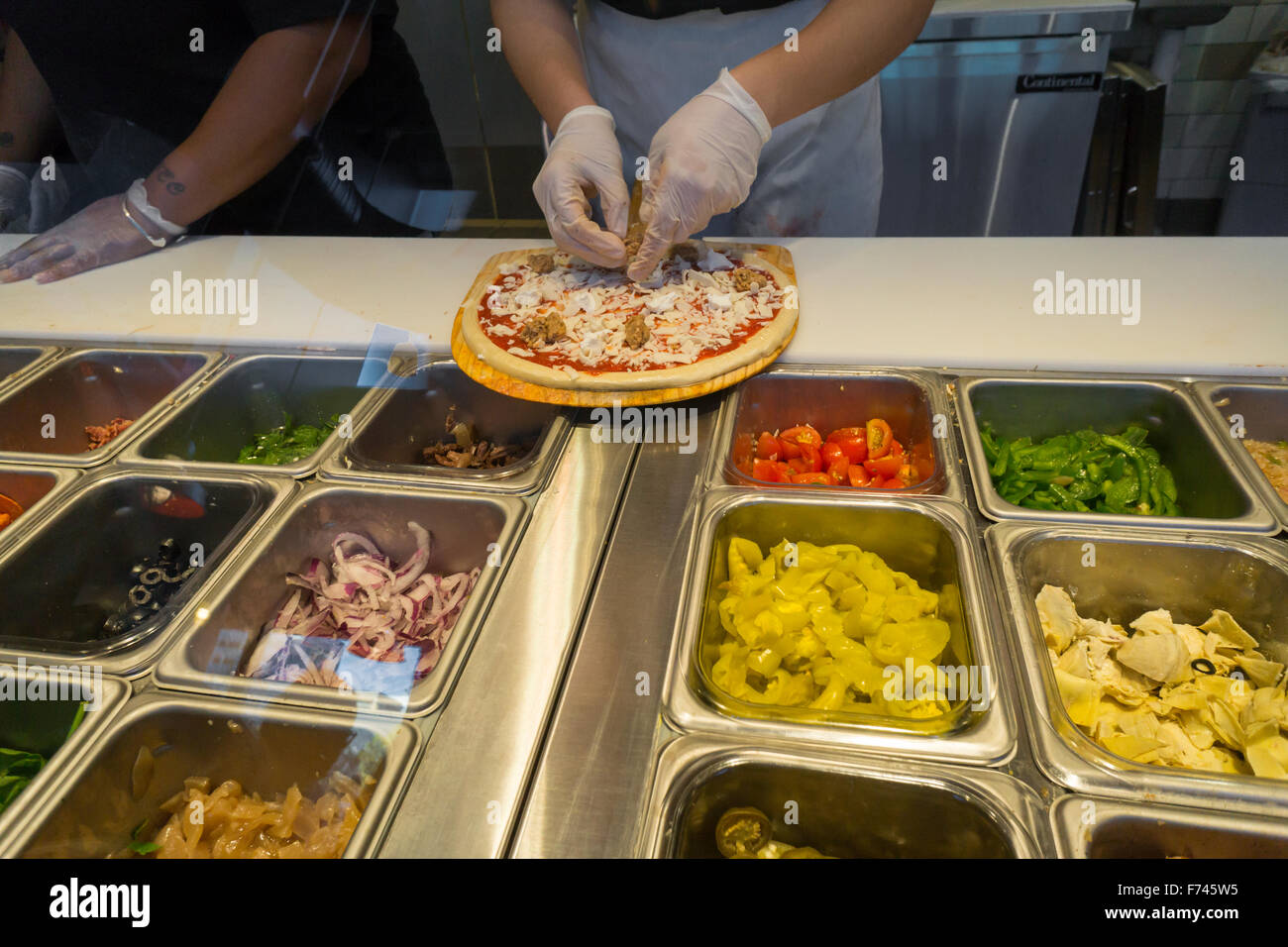 Employees construct a pizza right before the customers' eyes in ...
