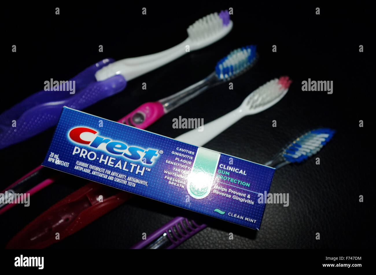 A row of four toothbrushes with a packet of toothpaste photographed ...