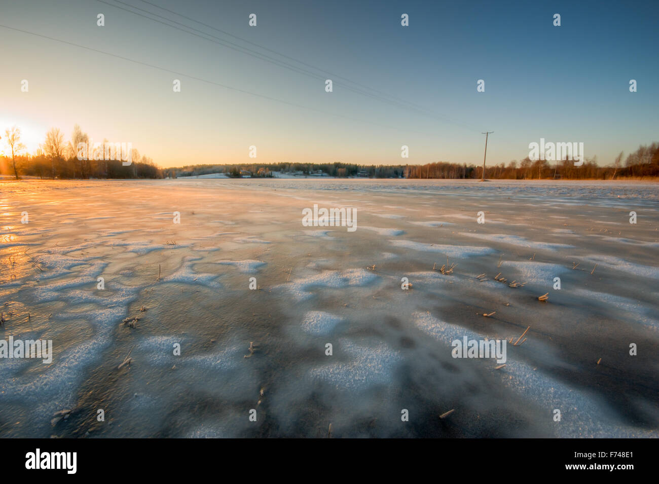 Sunset on icy field Stock Photo - Alamy