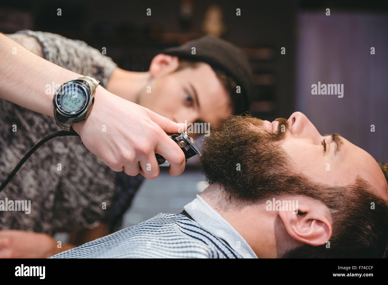 Attractive bearded man getting his beard shaved by modern barber in ...