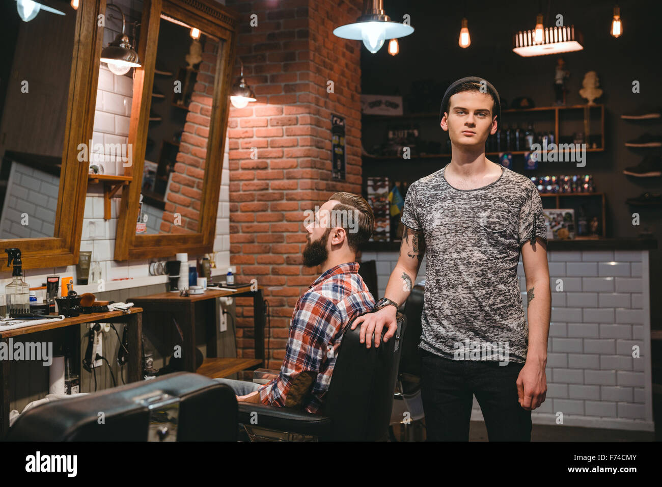 Young modern barber on his workplace with client in hair salon Stock ...