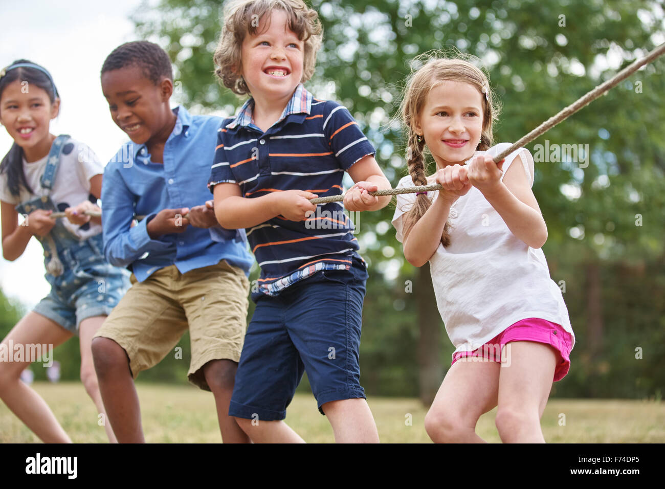 Group of kids pulling a rope at the park Stock Photo - Alamy