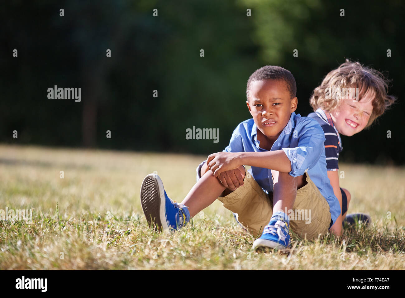 Two kids sitting on the grass in summer together Stock Photo - Alamy