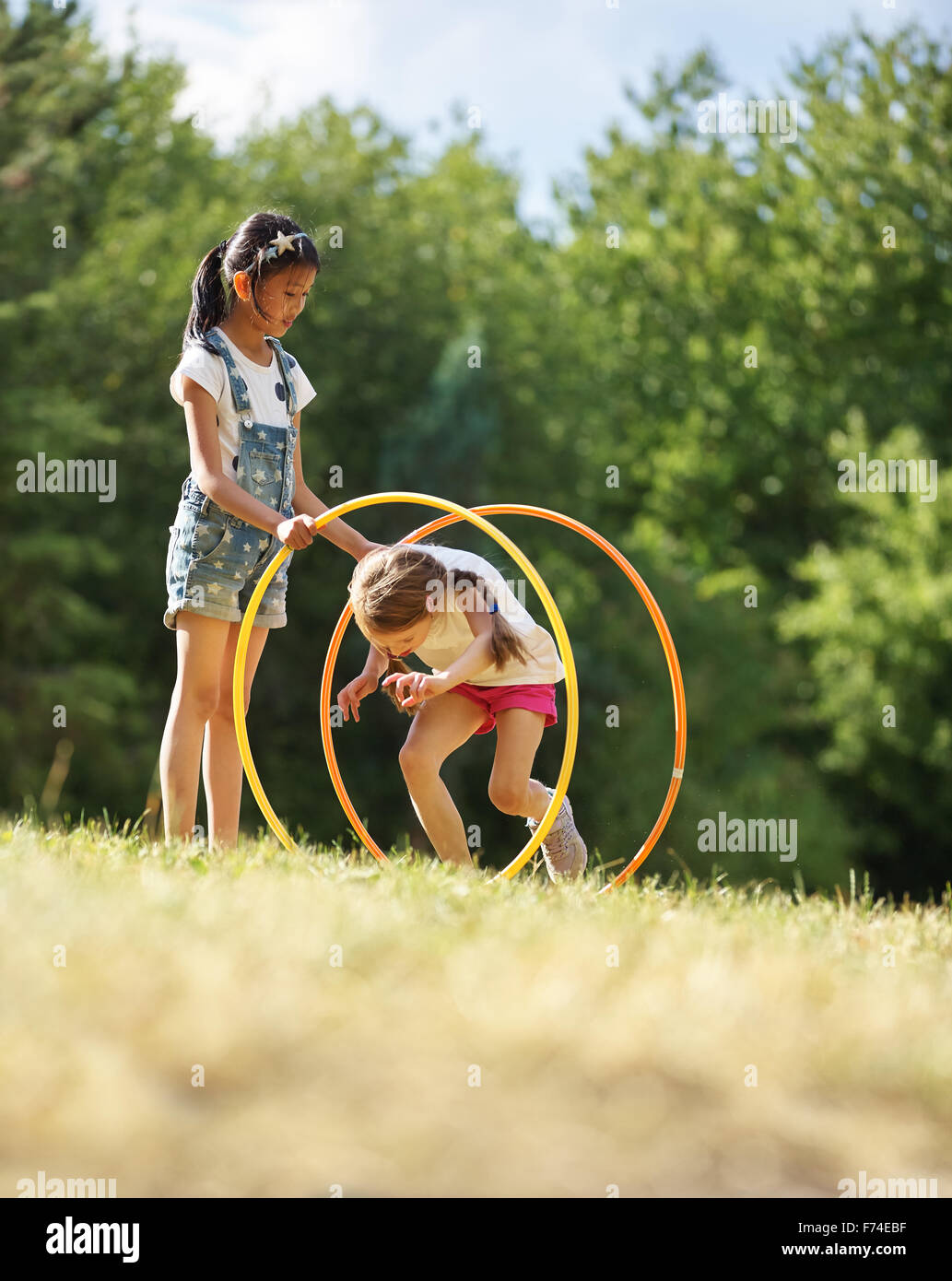 Two girls with hula hoops playing at the park Stock Photo - Alamy