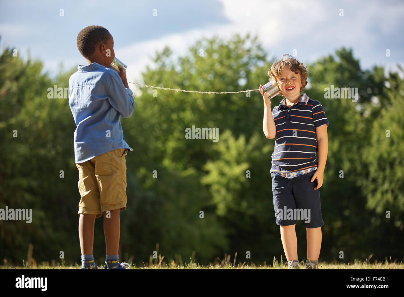 Two boys play with tin can telephone playing in the nature Stock Photo ...