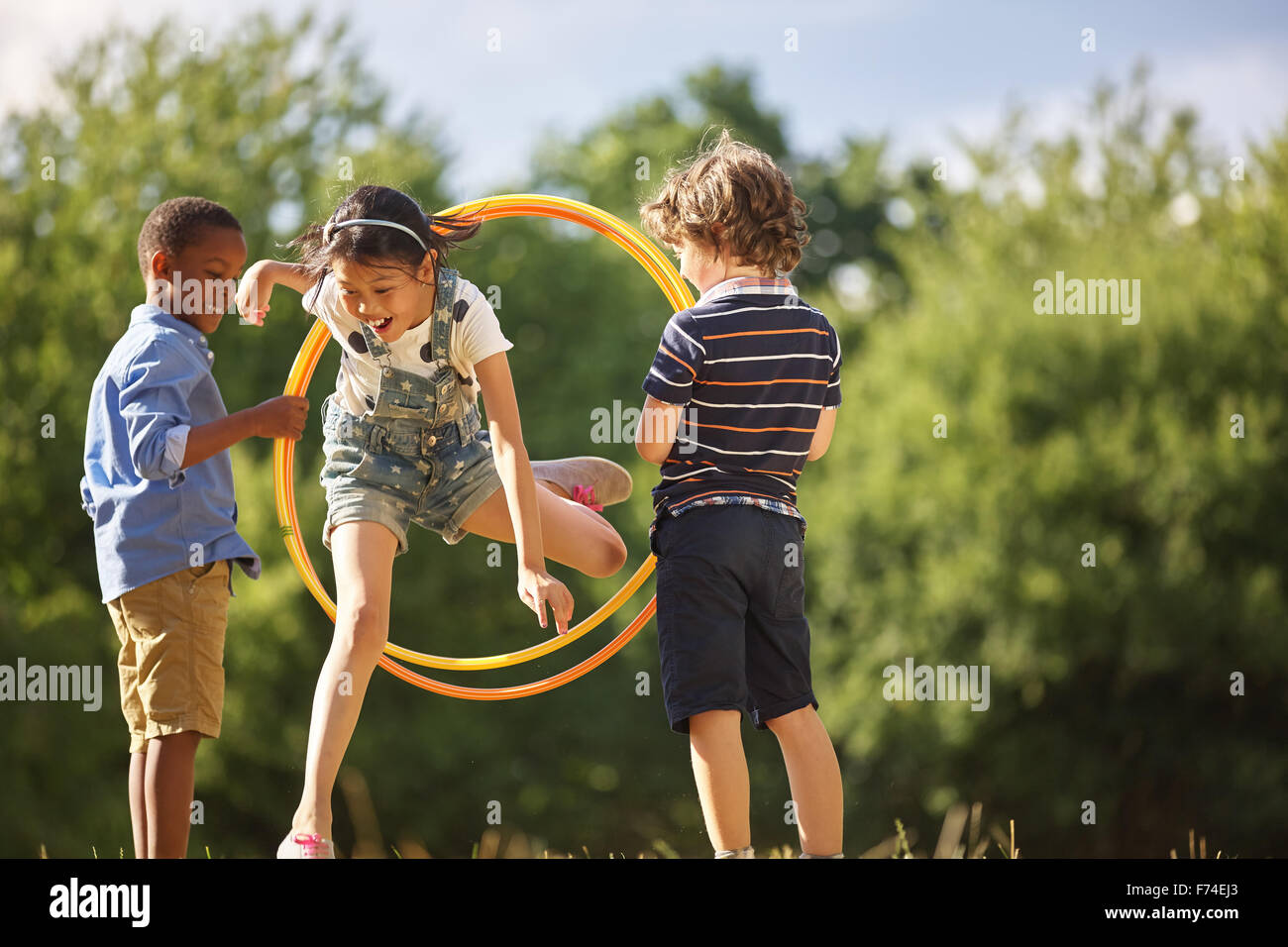 Girl jumps thourgh hula hoop while her friends hold it Stock Photo - Alamy