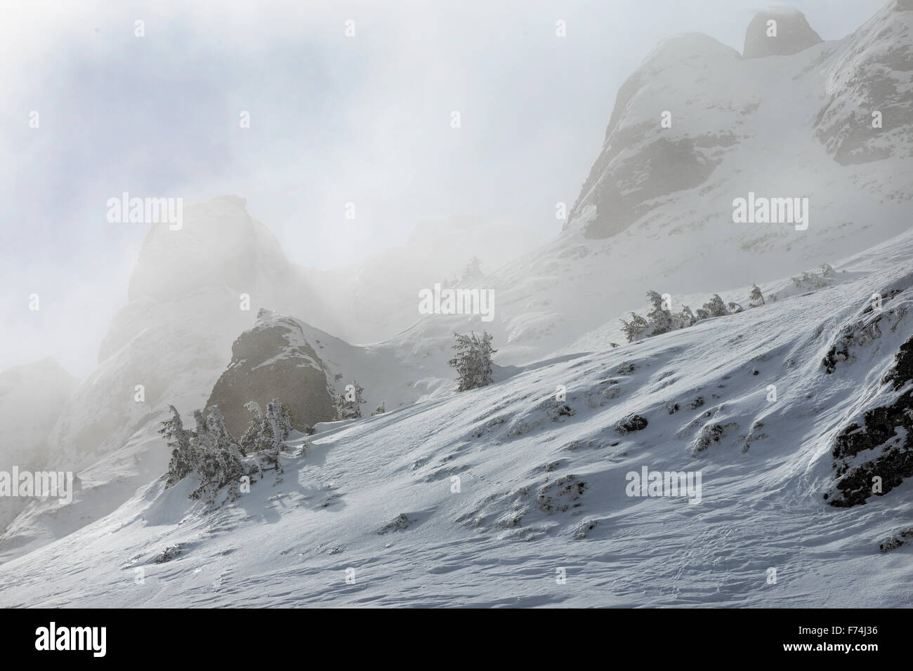 Snow covered beautiful mountain peaks in fog Stock Photo - Alamy