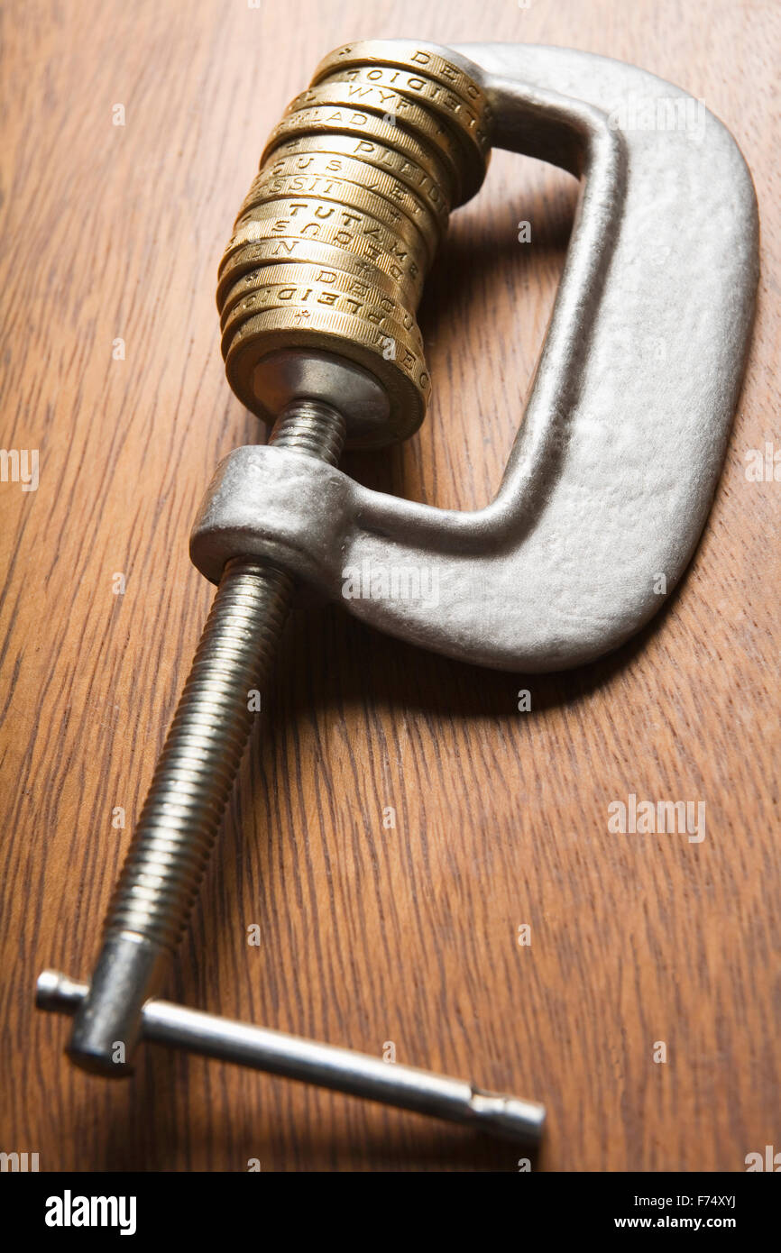 Stack of pound coins in vice Stock Photo - Alamy