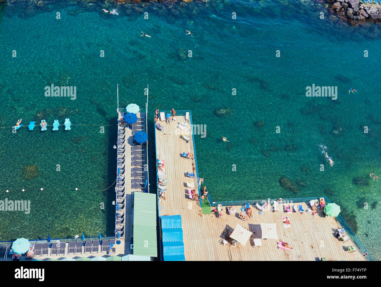 Holidaymakers on sunbathing platform and swimming in the Tyrrhenian Sea ...