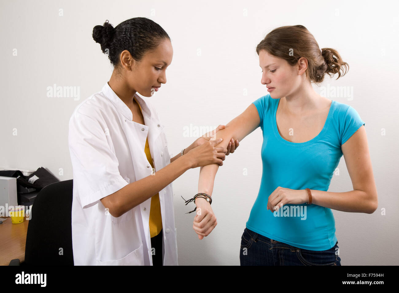 Checking her patient's arm Stock Photo - Alamy
