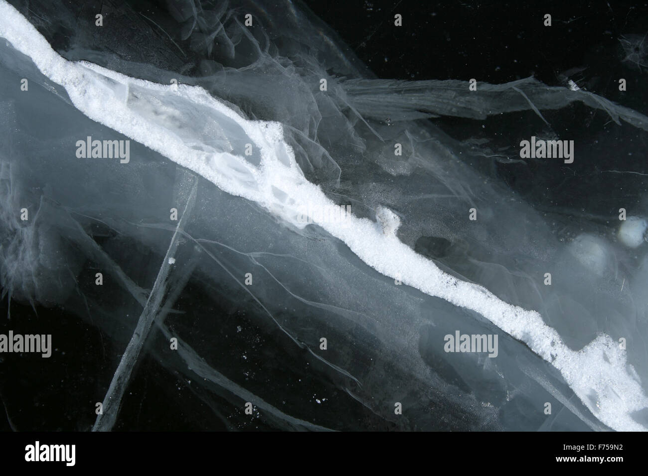 Cracked snowy ice, deep black water Stock Photo - Alamy