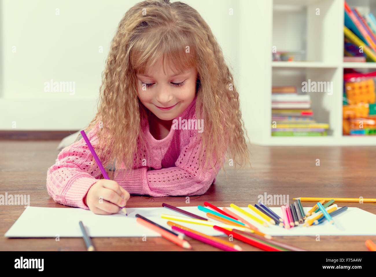 Little beautiful girl draws pencil on the floor in children's room ...