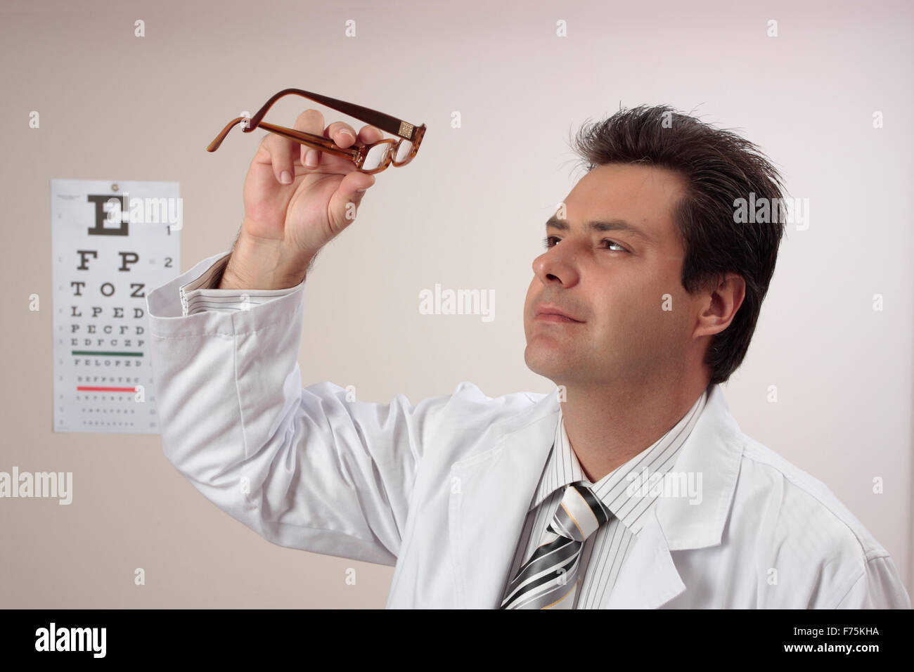 Optometrist inspecting eye glasses Stock Photo - Alamy