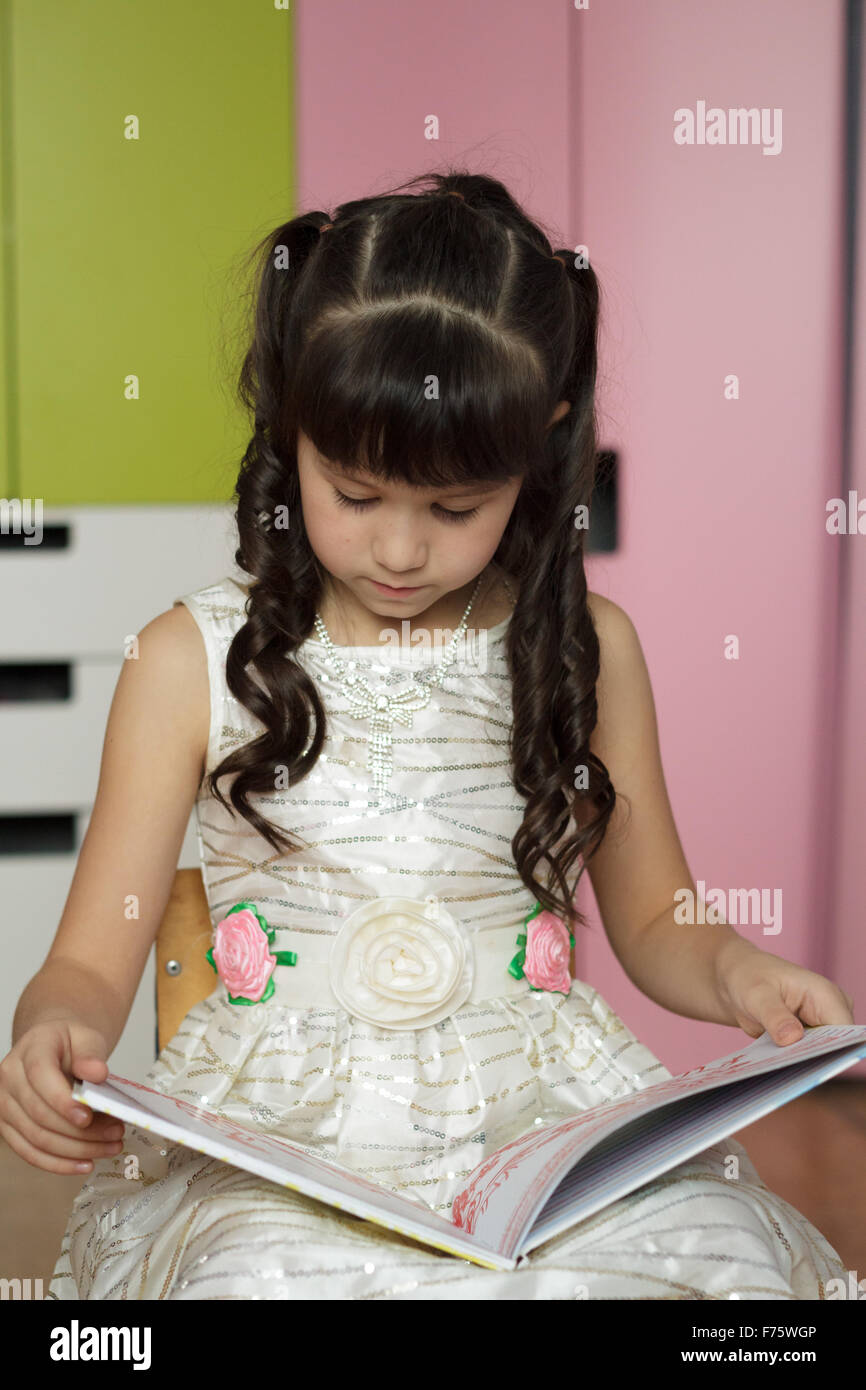 Beautiful little girl reading a book Stock Photo - Alamy