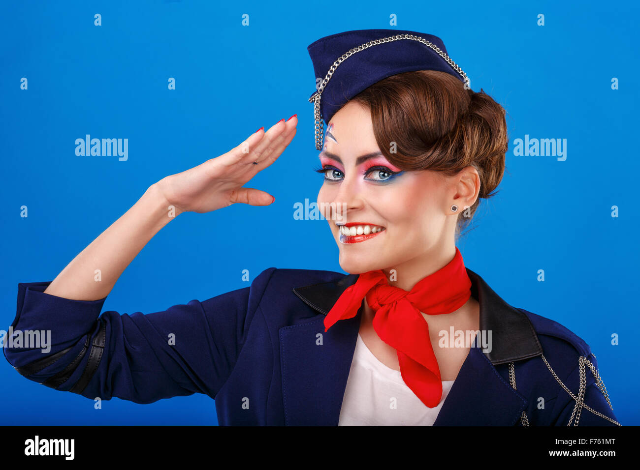 Stewardess with face art salutes. Young attractive girl in a blue suit ...