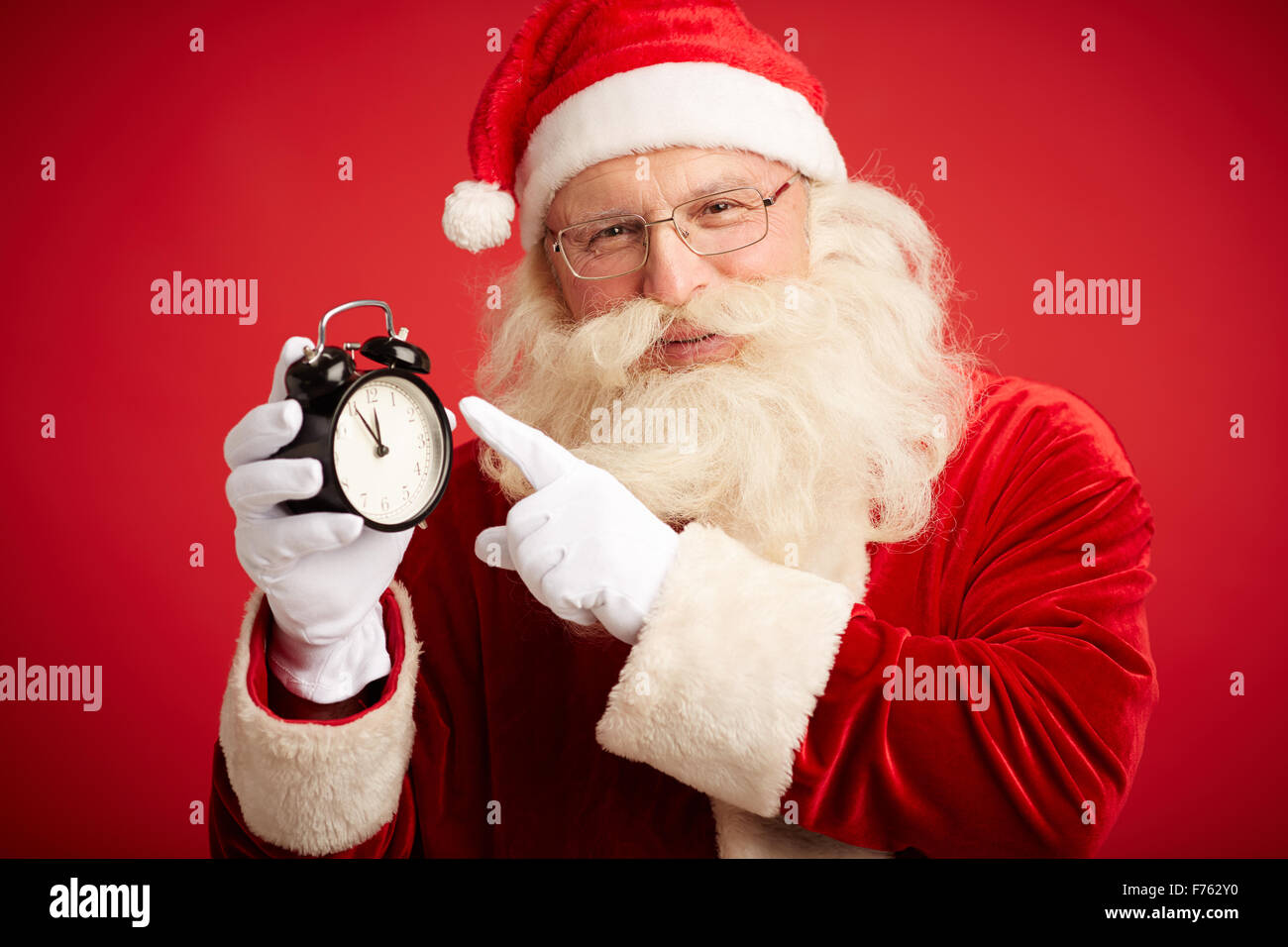 Happy Santa Claus showing at alarm-clock and looking at camera Stock ...