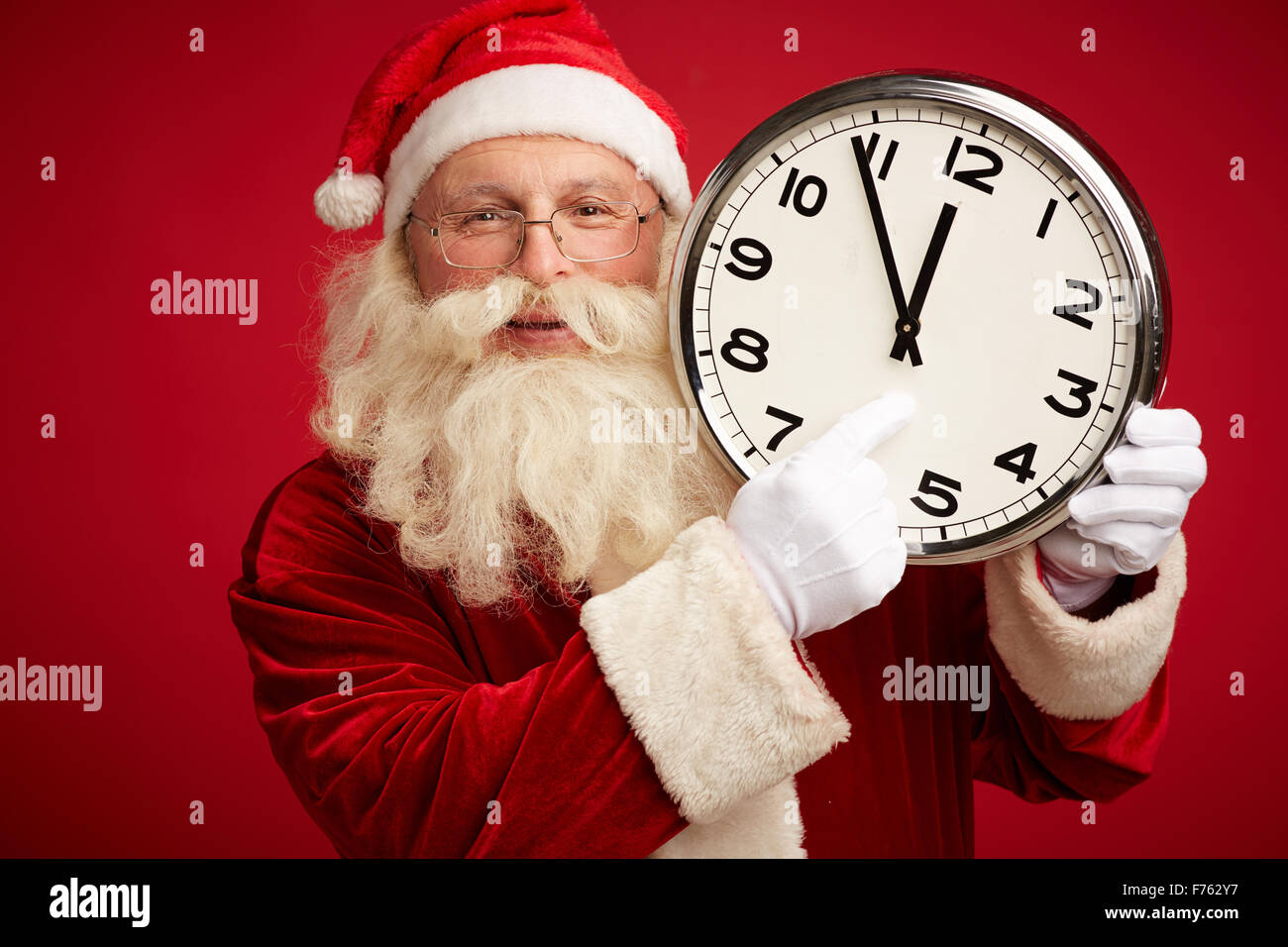 Happy Santa holding clock showing five minutes to twelve Stock Photo ...