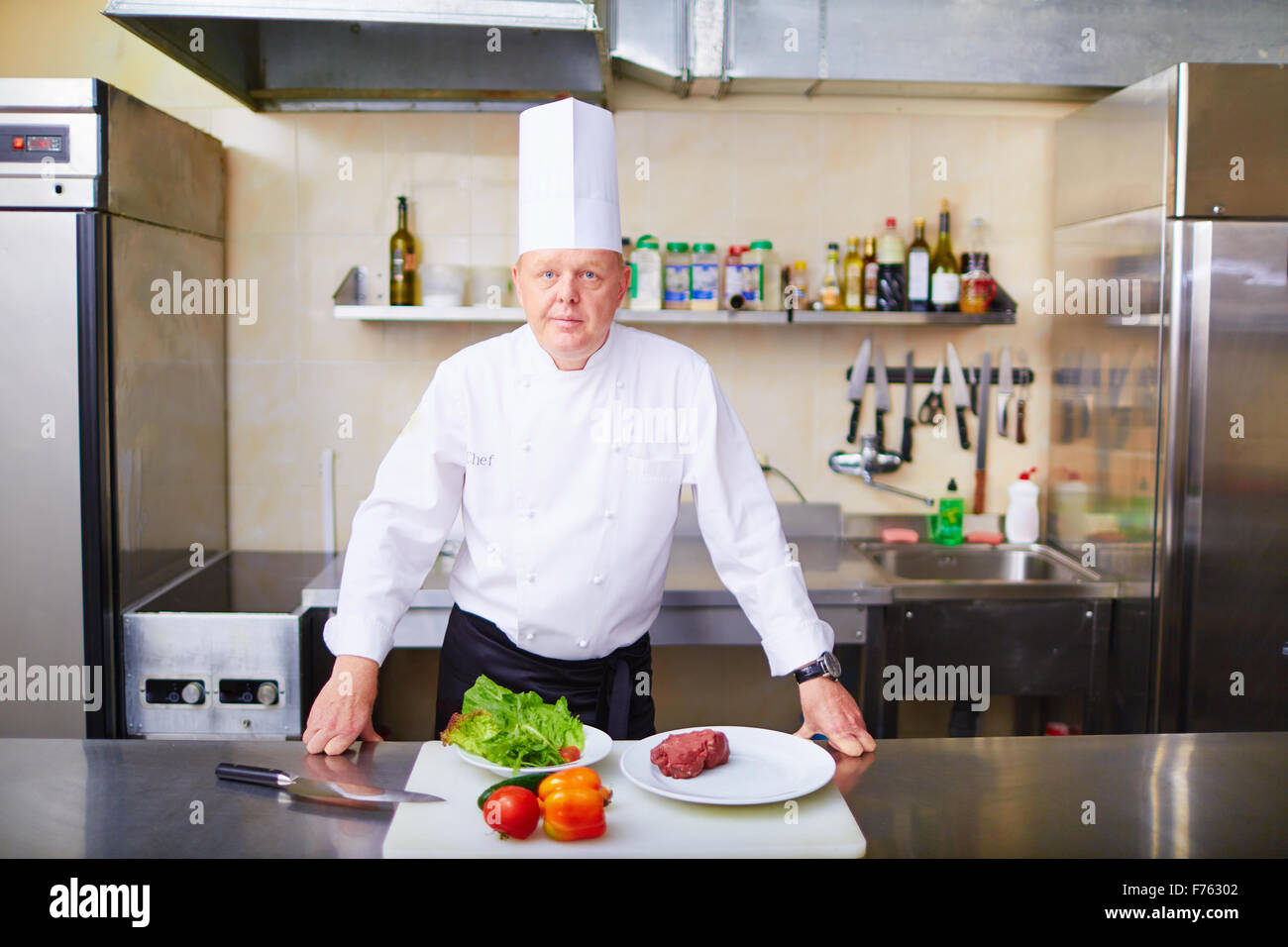 Serious male chef standing near the food ingredients and ready for work ...