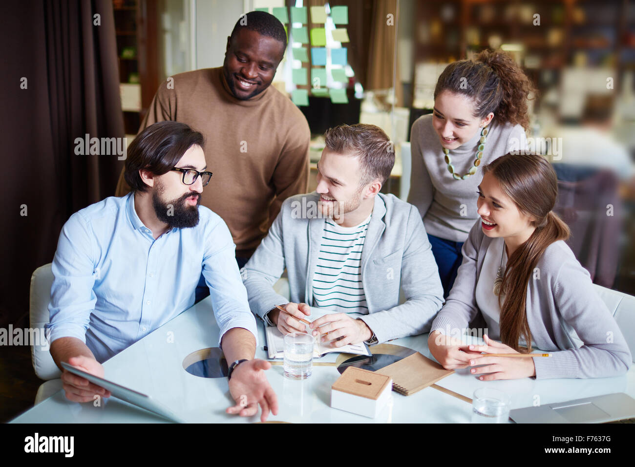 Bearded businessman with touchpad explaining his idea to co-workers ...