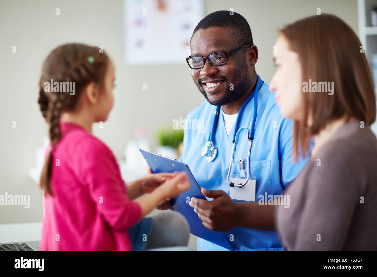 Happy doctor looking at little girl in clinics Stock Photo - Alamy