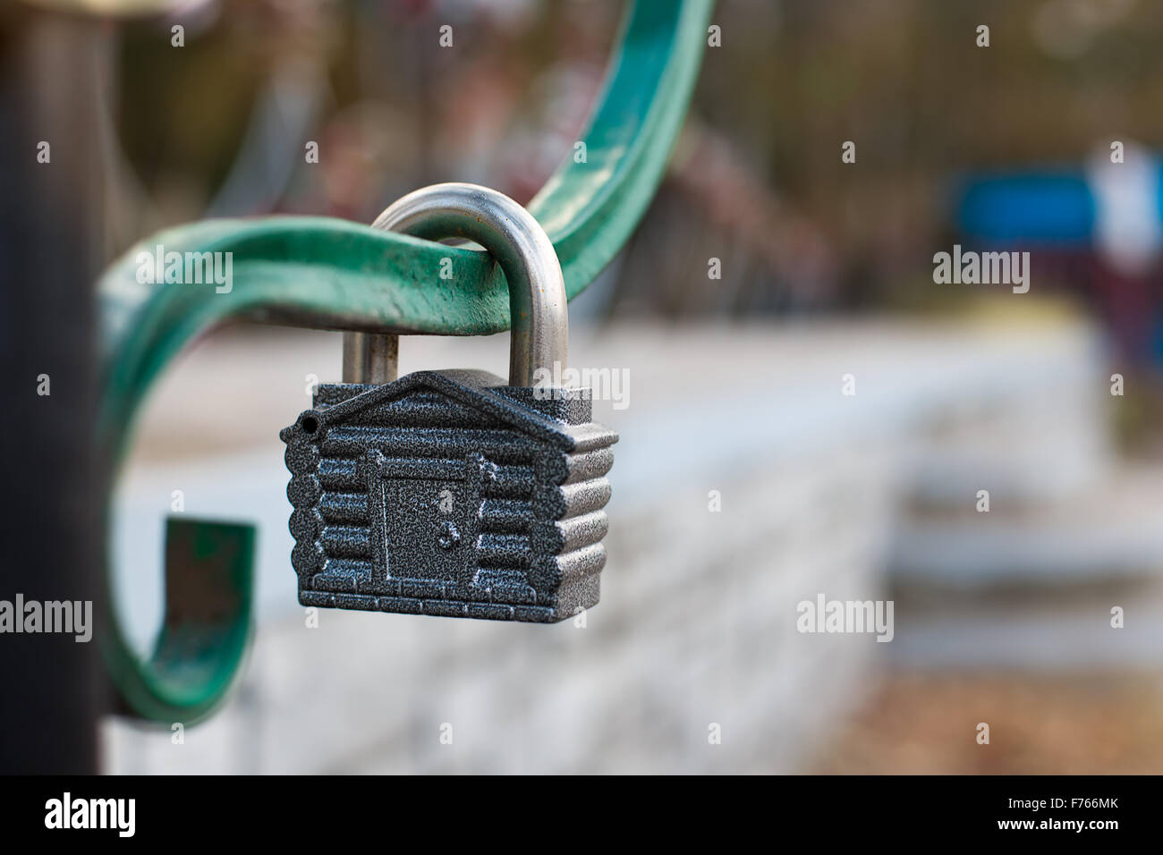 Padlock in form of house hanging on green metal arc Stock Photo - Alamy