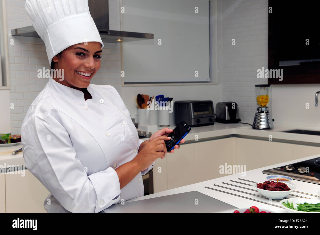 Happy chef cooking in kitchen and typing sms Stock Photo - Alamy