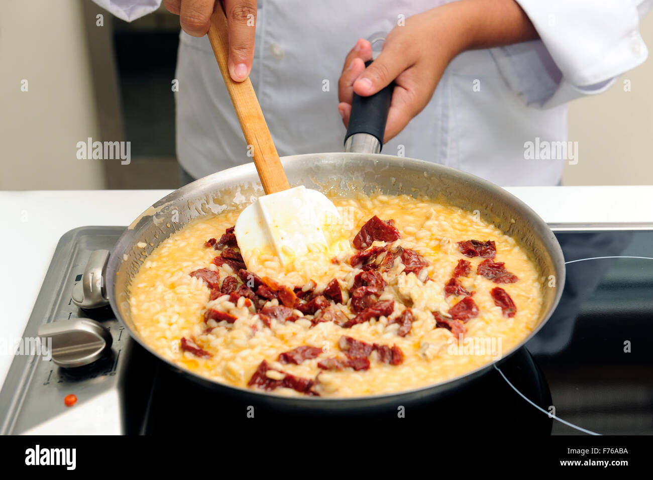 Chef cooking risotto with dried tomato stirring Stock Photo - Alamy