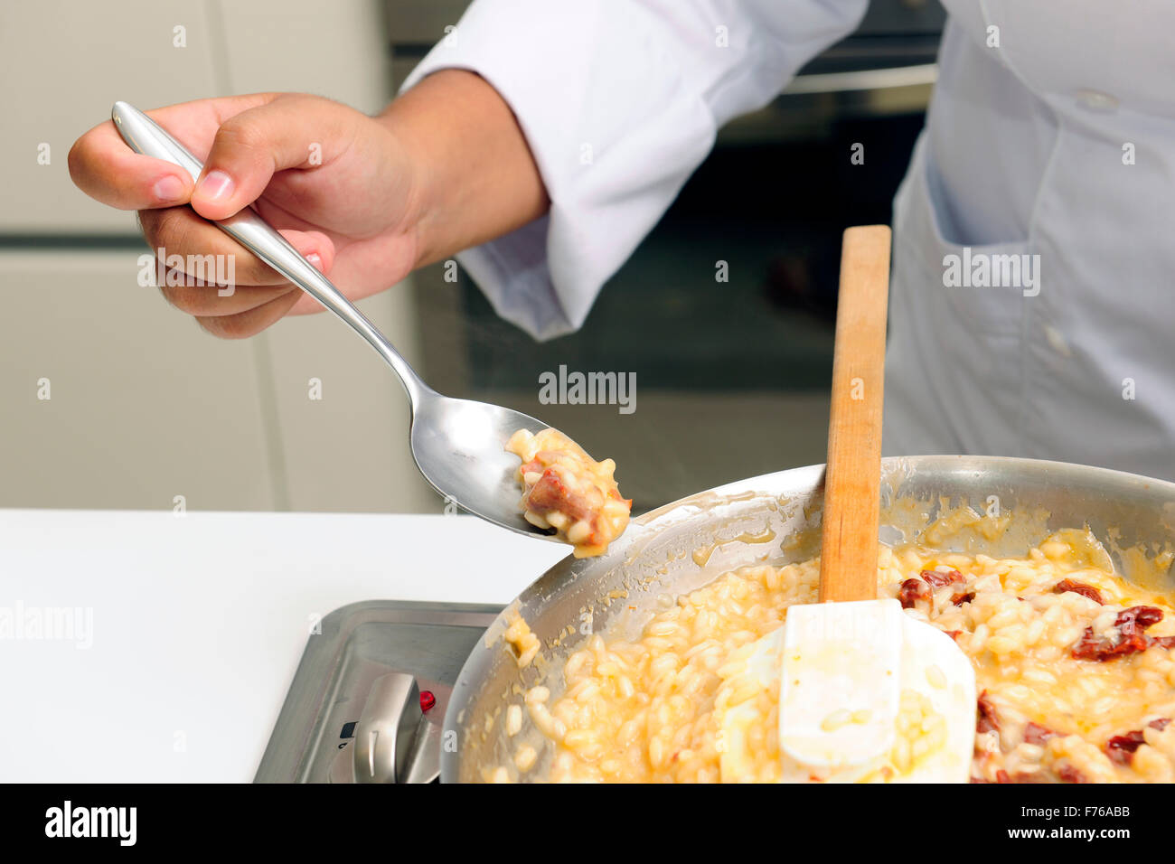 Chef cooking risotto with dried tomato stirring Stock Photo - Alamy