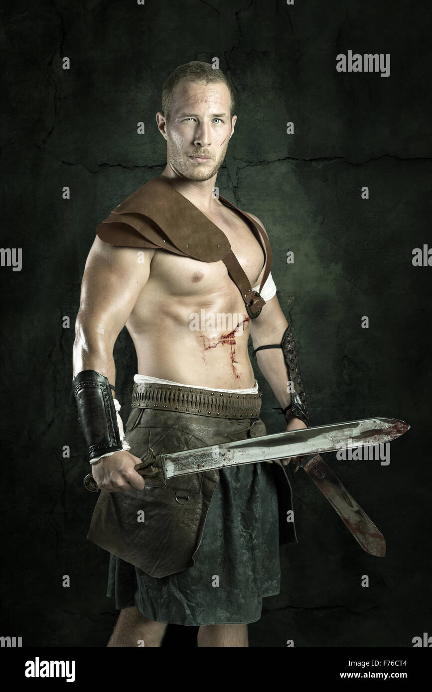 Gladiator posing isolated in a dark background Stock Photo - Alamy