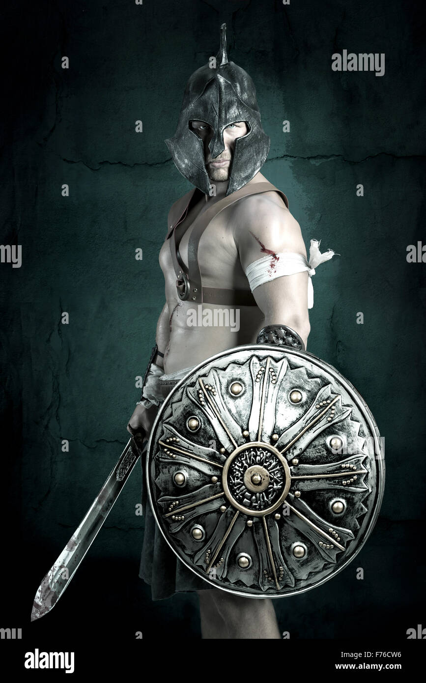 Gladiator posing isolated in a dark background Stock Photo - Alamy