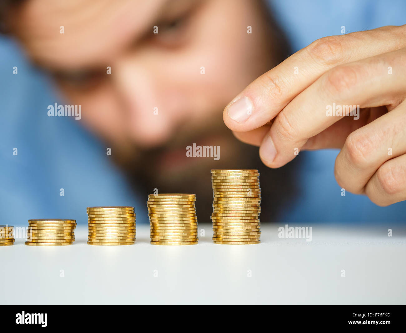 Savings, beard business man stacking gold coins into increasing columns ...