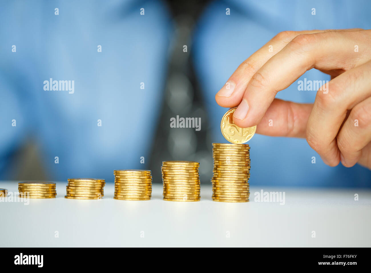 Savings, male hand stacking gold coins into increasing columns Stock ...