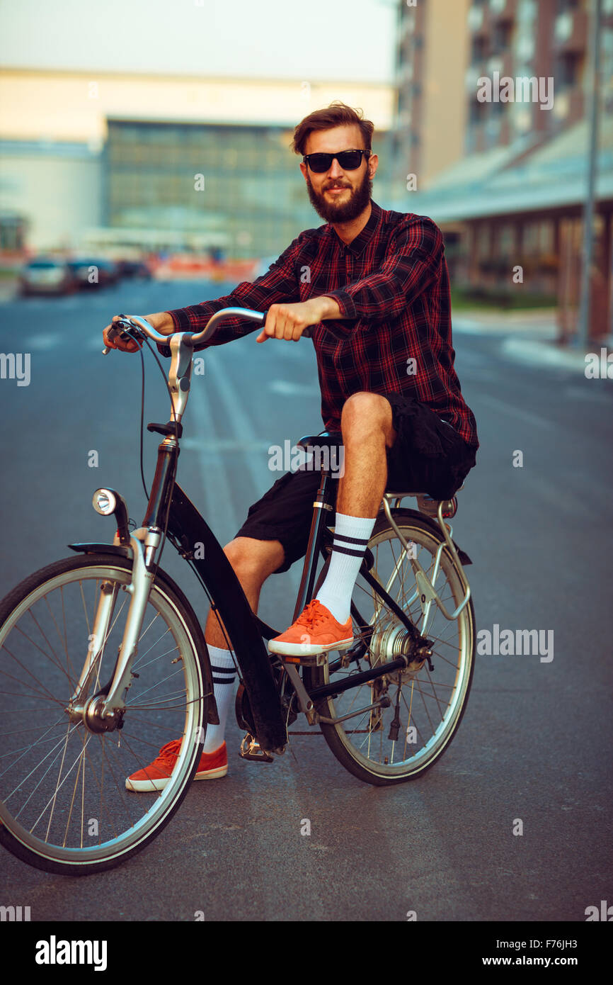 Young stylish man in sunglasses riding a bike on city street Stock ...