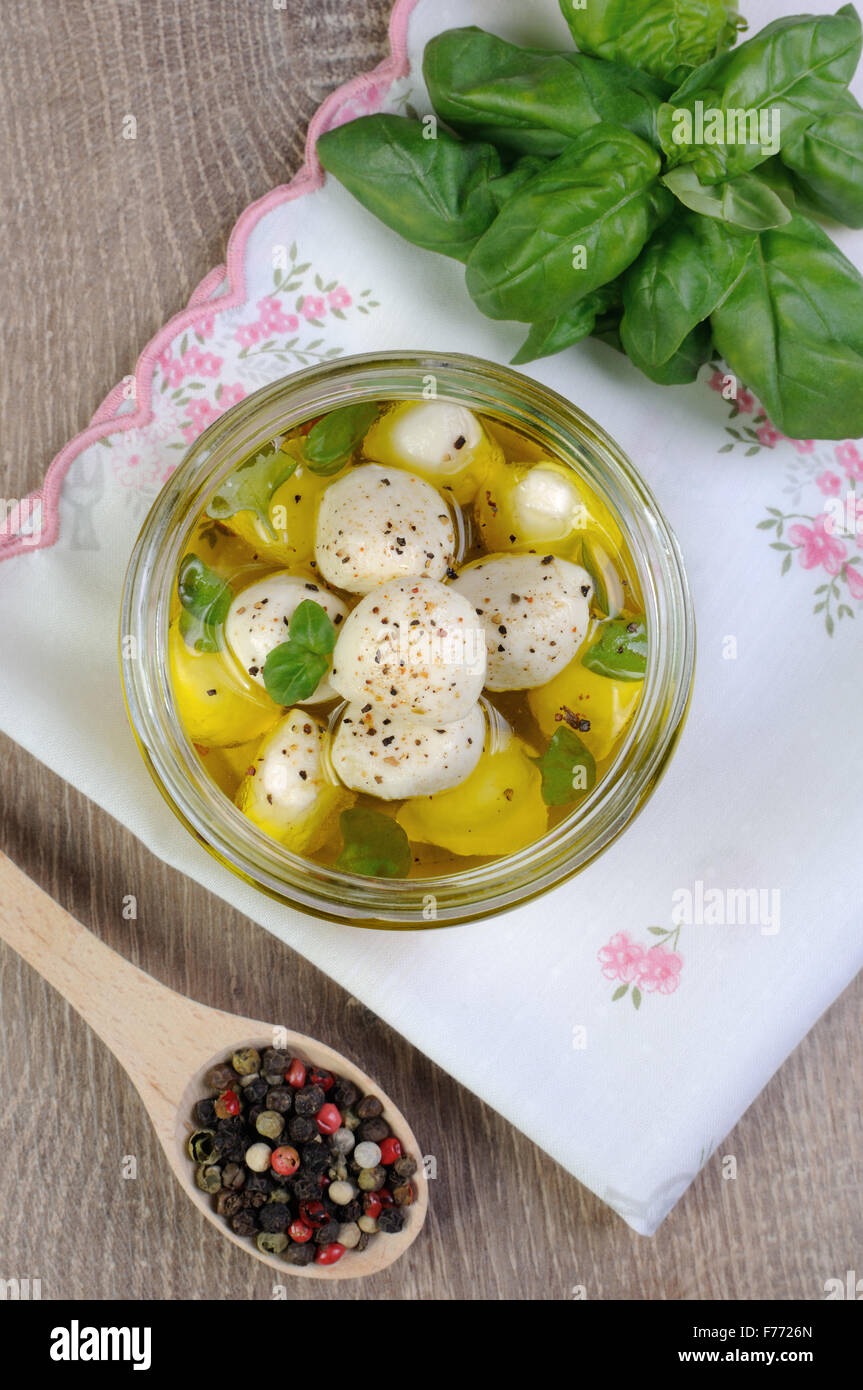 Baby mozzarella in olive oil with herbs in a glass jar Stock Photo - Alamy